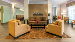 Um lobby moderno com um conjunto de sofás, uma mesa de centro e quadros nas paredes.