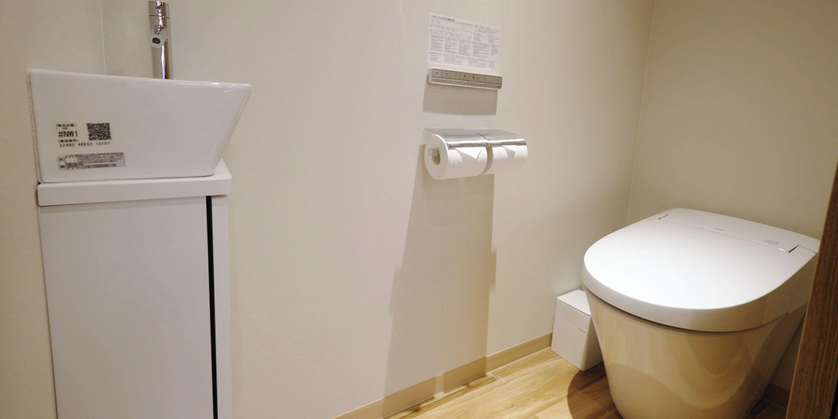 Uma casa de banho pequena e limpa, com sanita, lavatório e dispensador de papel.