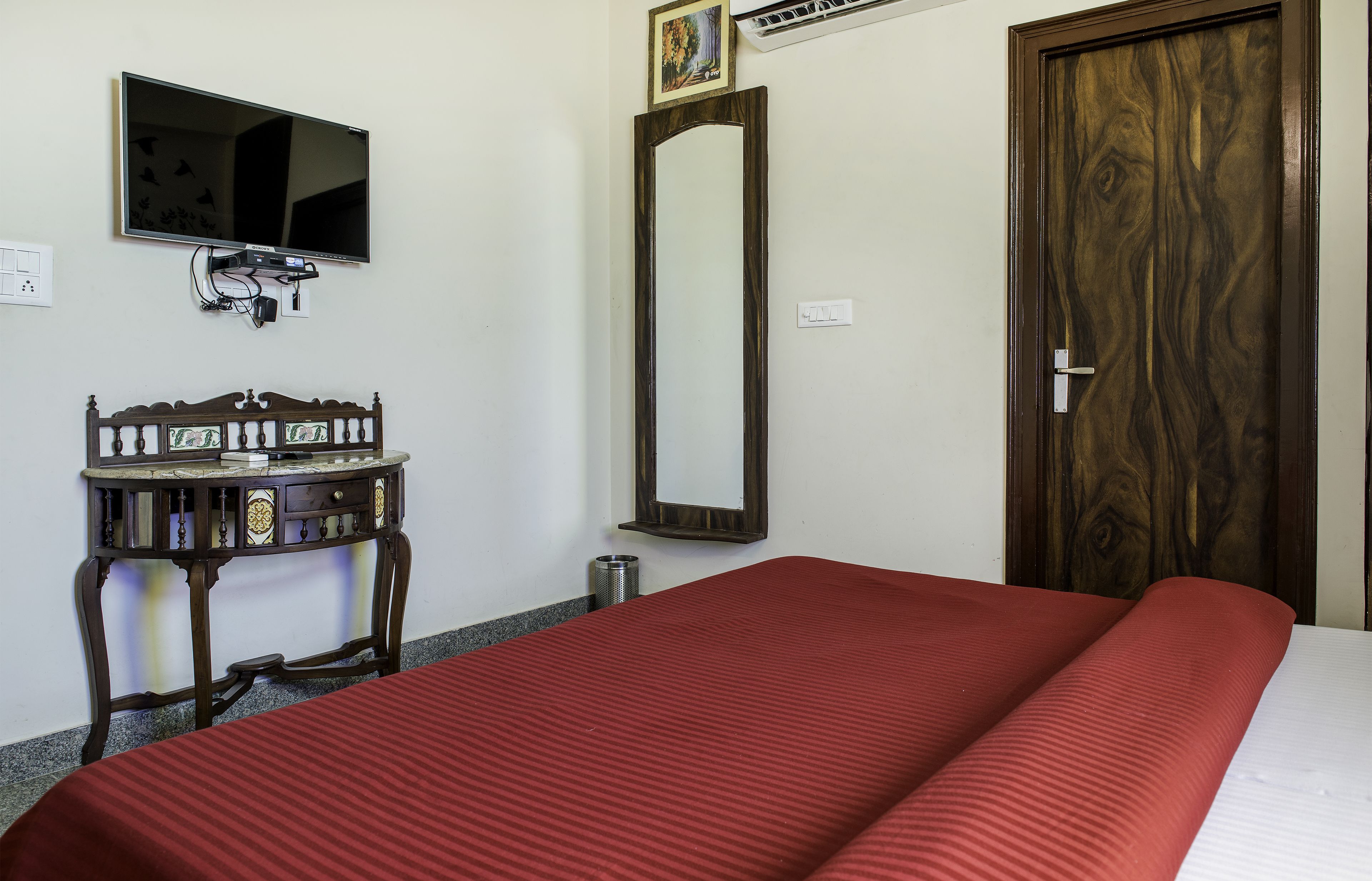 Um quarto com uma cama, penteadeira de madeira, espelho e porta.