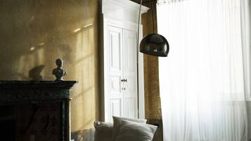 Quarto com cama, porta branca, luminária na parede e estátua na lareira.
