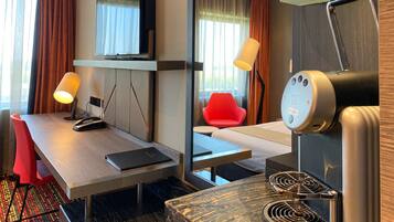 Quarto de hotel com escrivaninha, cadeira, cama e máquina de café.