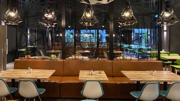 Restaurante moderno com área de estar central, tetos altos e luminárias geométricas.