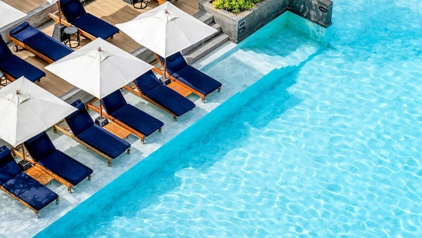 Uma área de piscina com espreguiçadeiras e guarda-sóis.