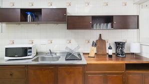 Cozinha equipada com micro-ondas, pia, suporte para facas e cafeteira.