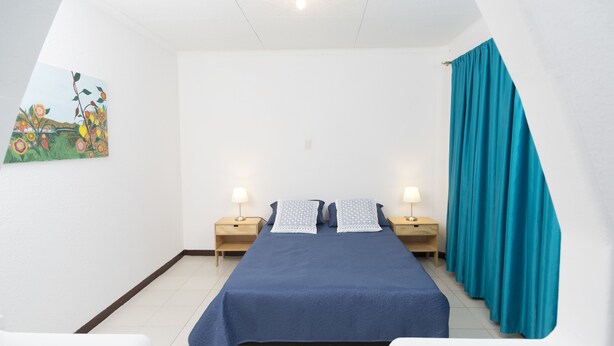 Um quarto com uma cama, duas mesas de cabeceira e um quadro na parede.