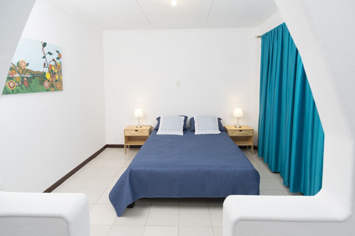 Um quarto com uma cama, duas mesas de cabeceira e um quadro na parede.