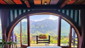 Quarto com cama grande, vista para montanhas e teto de madeira.