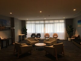 Uma sala de conferências moderna com uma grande janela, várias cadeiras, uma mesa redonda e um vaso de planta.