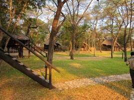 Um parque com cabanas de colmo, uma escadaria de pedra e um caminho pavimentado.