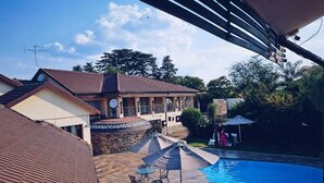 Piscina com área de estar no pátio, assentos externos e um edifício com telhado telhado.