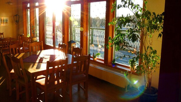 Uma sala de jantar com móveis de madeira, janelas amplas e vista para uma varanda.
