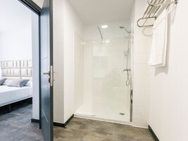 Casa de banho moderna com cabine de chuveiro em vidro, uma banheira branca e um porta-toalhas.