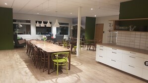 Cozinha moderna com uma longa mesa de madeira, cadeiras e um armário embutido branco.