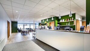 Um espaço de escritório moderno com balcão de recepção, área de estar e paredes com detalhes verdes.