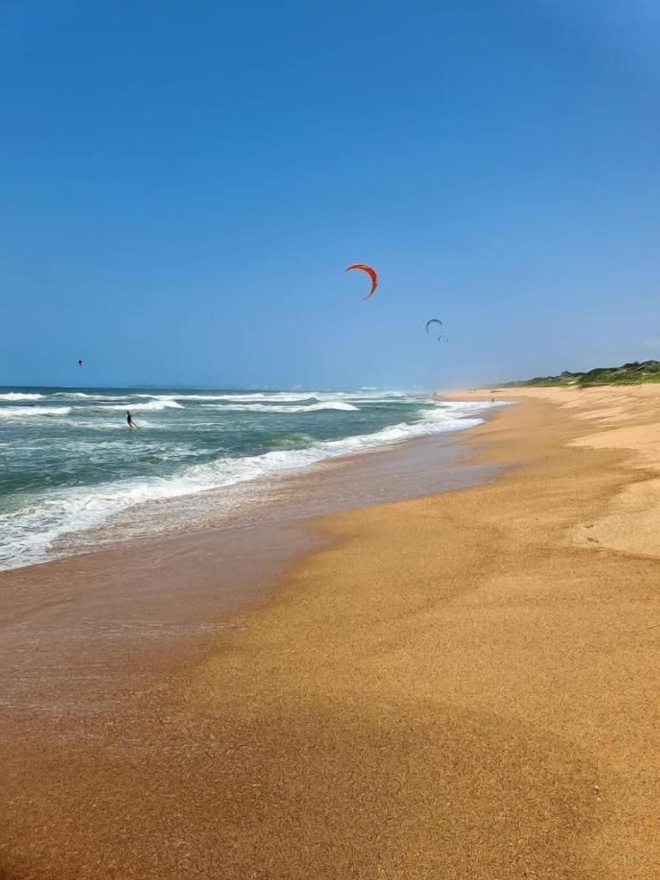 Uma praia com areal e ondas do oceano.