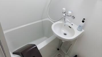 Um banheiro com pia branca, banheira e vaso sanitário. Há artigos de higiene pessoal no chão.