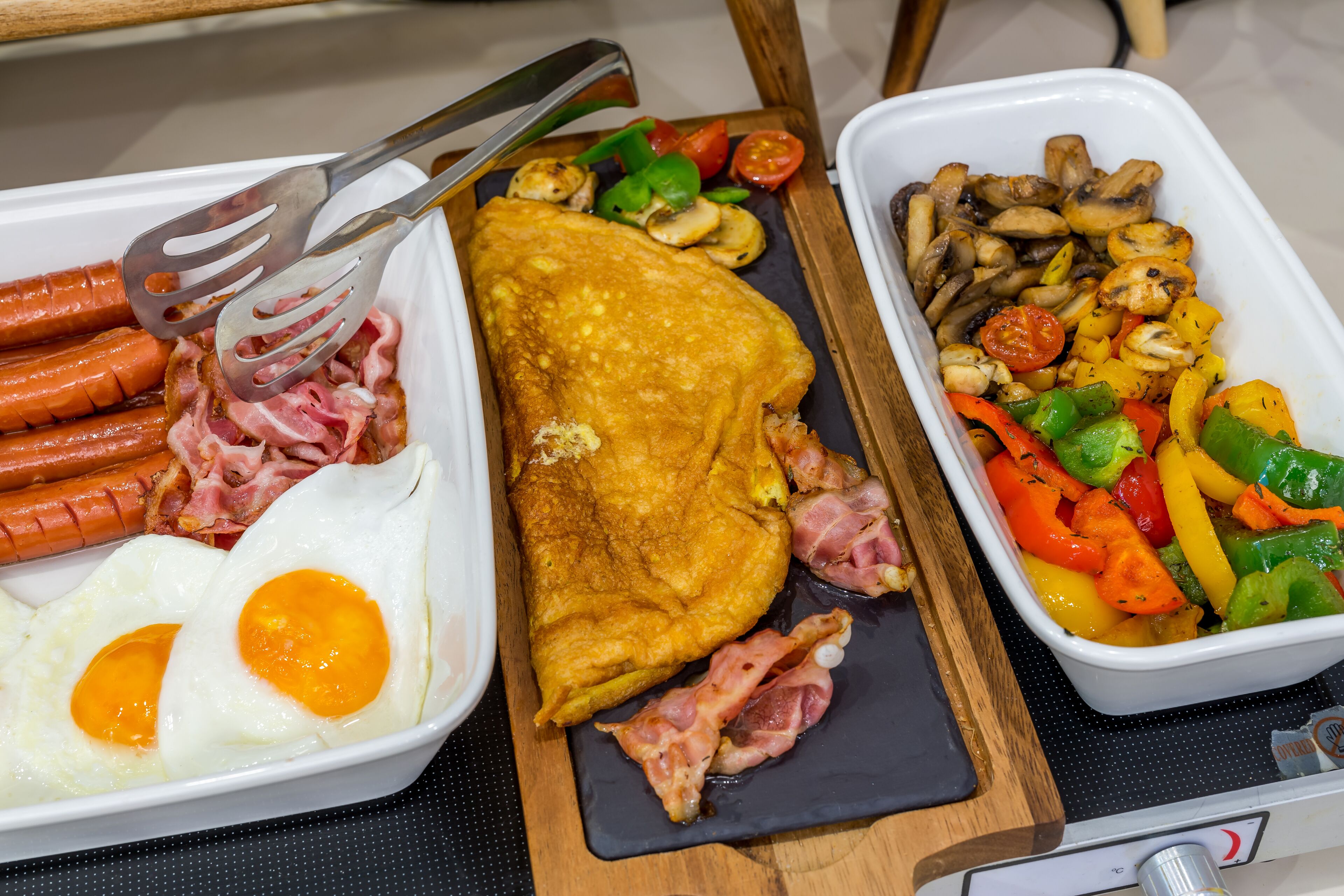 Bandeja de café da manhã com ovos, linguiça, bacon, cogumelos e pimentões.