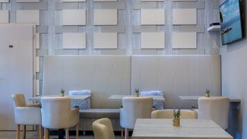 Um interior moderno com área de estar, com bancos e cadeiras estofadas, uma TV de tela plana na parede e um design de parede estampado.
