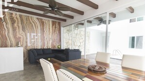 Uma sala de estar moderna com uma mesa de jantar de madeira, um sofá preto e uma parede de pedra.