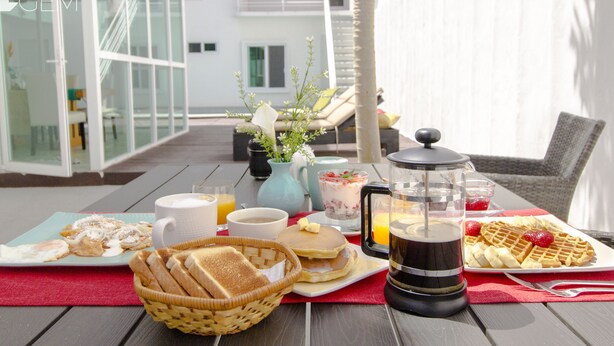 Mesa de café da manhã com panquecas, waffles, torradas, café e suco.