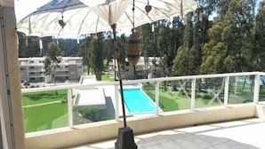 Varanda com vista para uma piscina e vegetação ao redor.