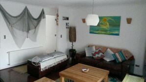 Uma sala de estar com um sofá, uma mesa de centro e um quadro na parede.
