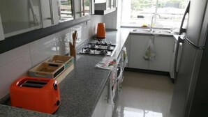 Uma cozinha com fogão a gás, pia e torradeira.
