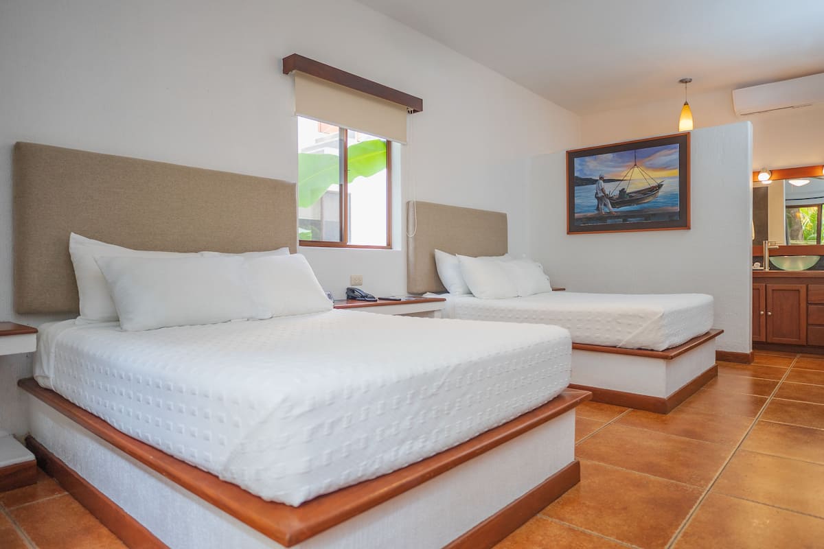 Quarto de hotel com duas camas, um quadro na parede e vista para o exterior.