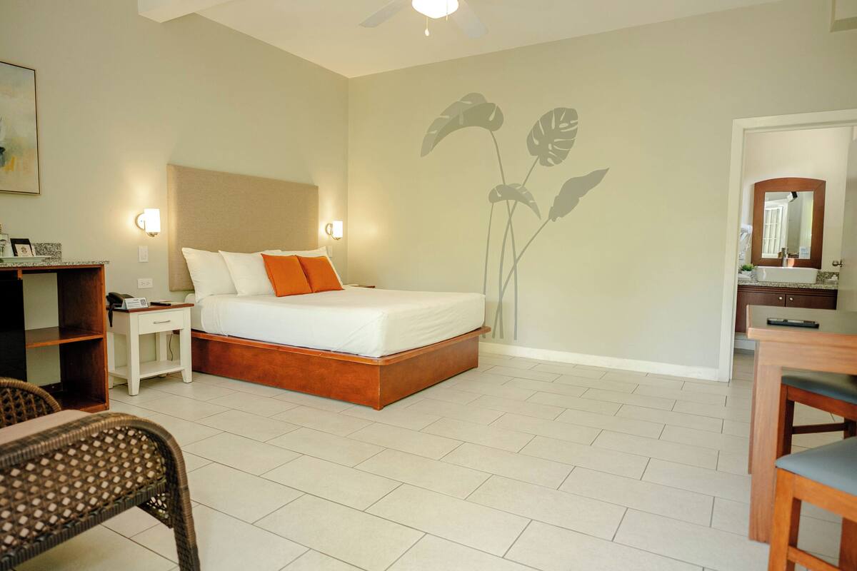 Quarto com cama, mesa de cabeceira e luminária.