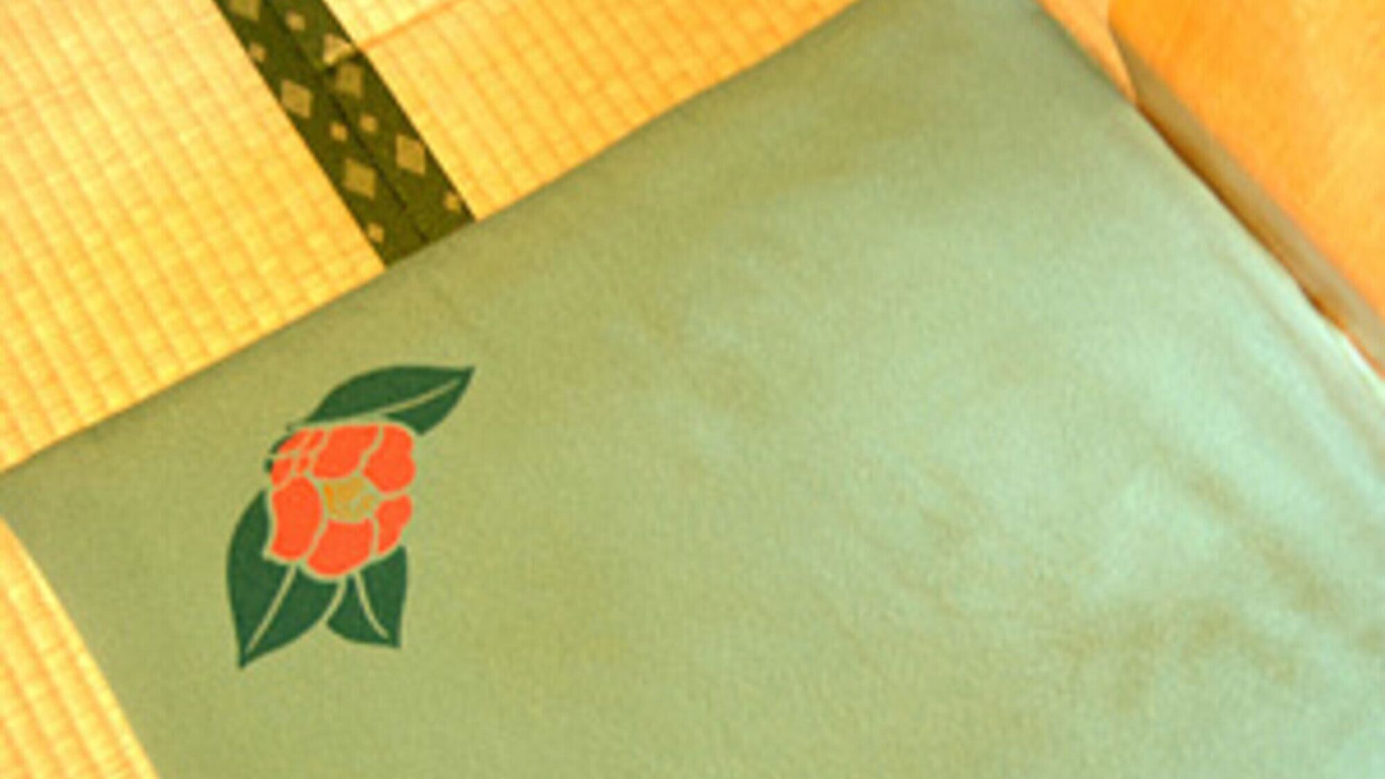 Almofada verde com um desenho de flor e folha vermelhos.