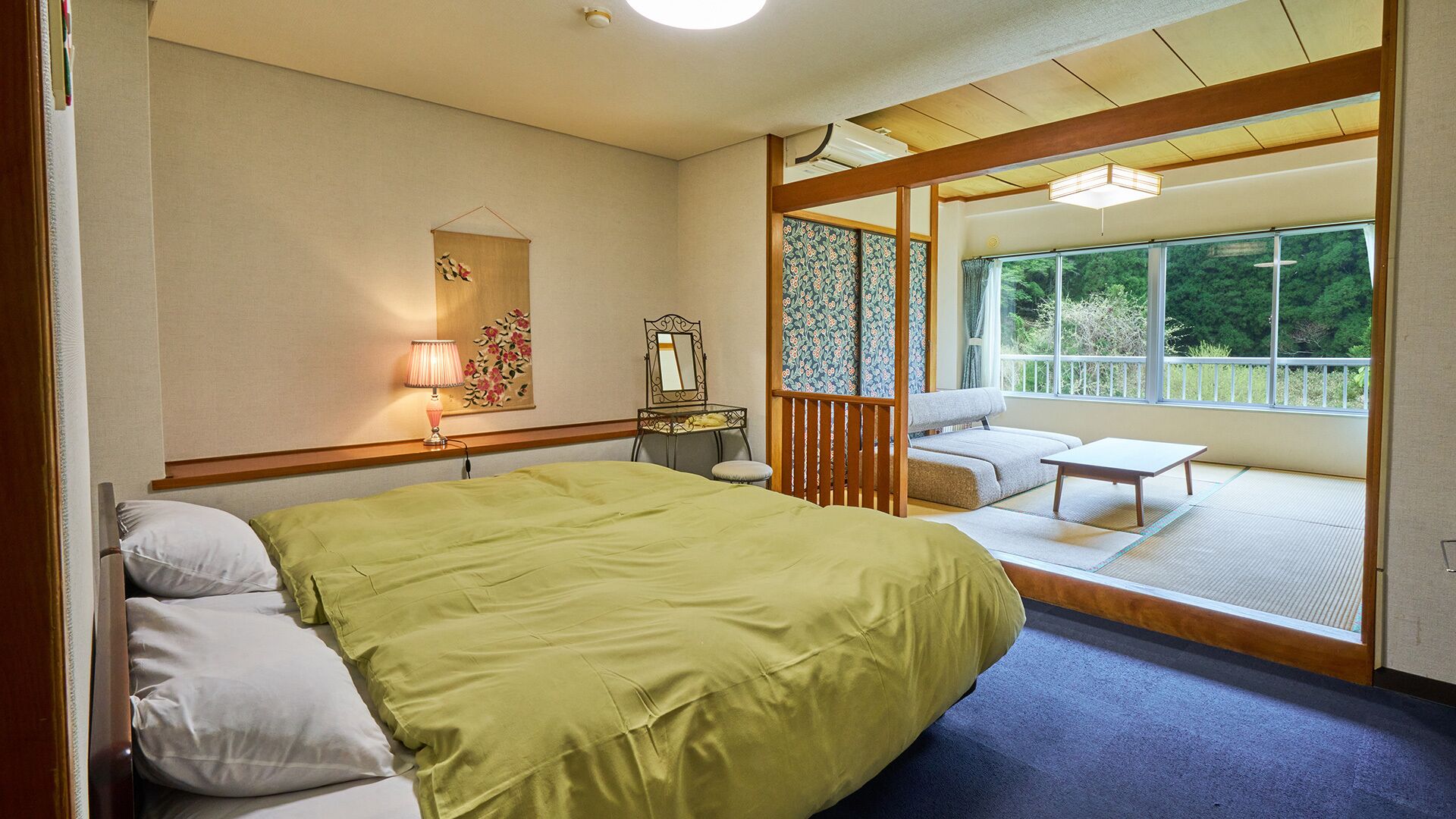 Quarto com cama, escrivaninha, cadeira, janela e vista para o exterior.
