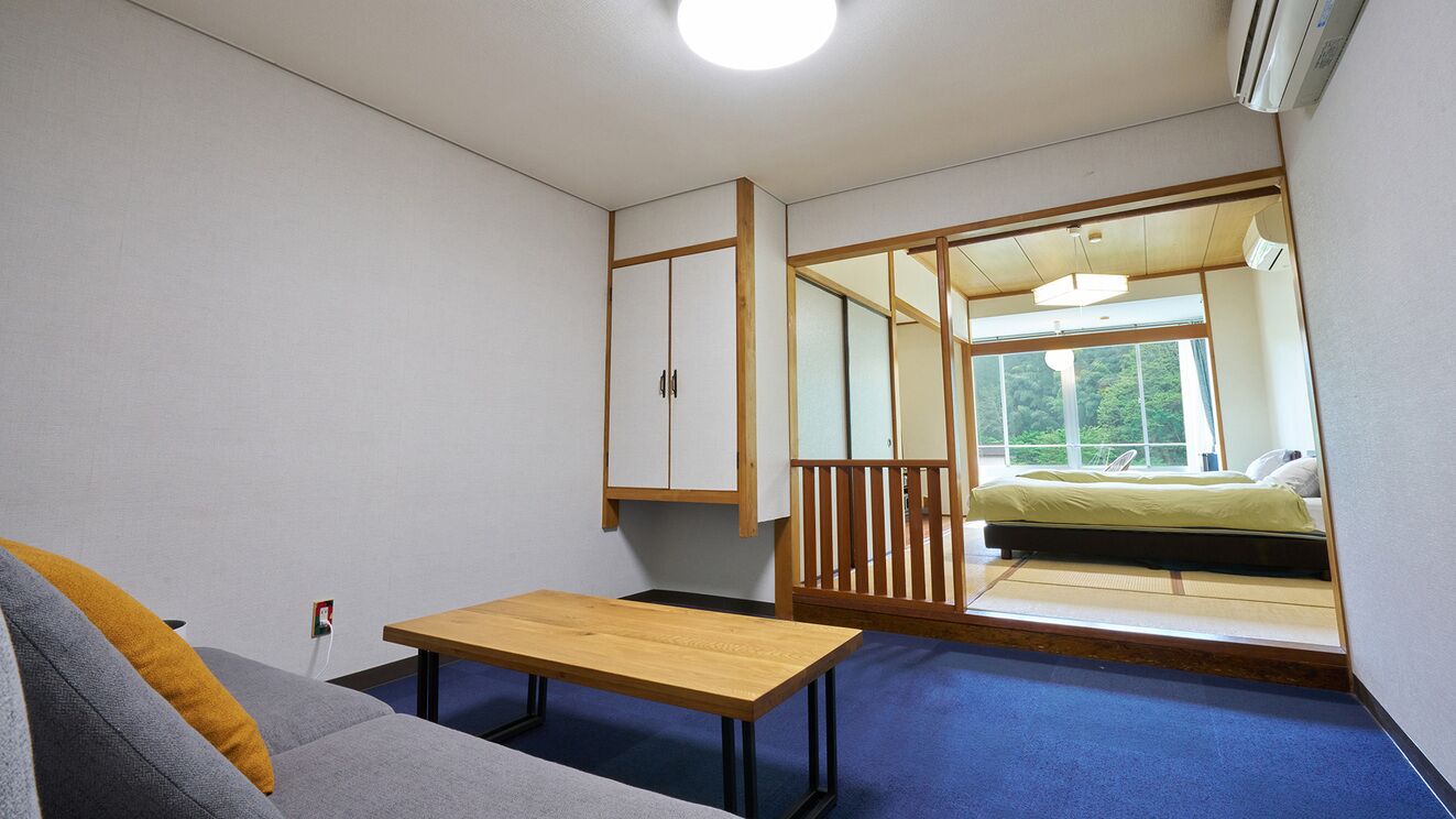 Quarto com sofá, uma mesinha, cama com vista e portas deslizantes.