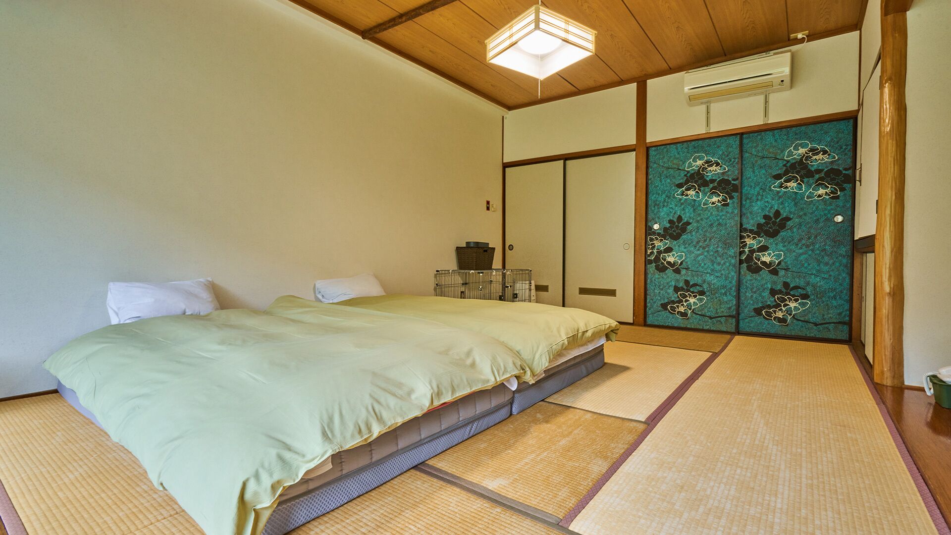 Quarto tradicional japonês com tatames, cama baixa e portas corrediças com estampas florais.