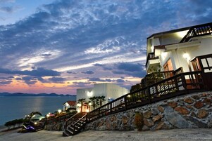 Um hotel à beira-mar com uma escadaria de pedra que dá para uma varanda, com vista para o mar.