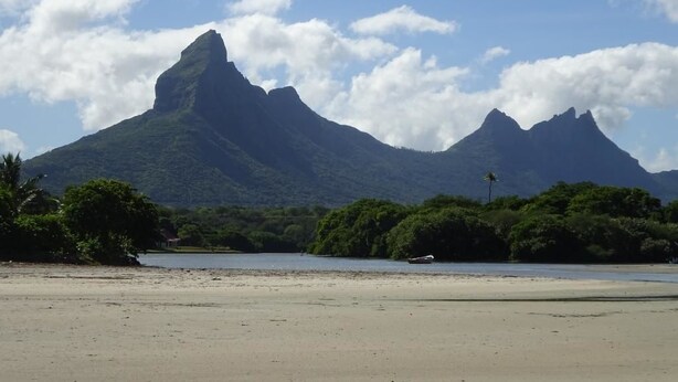 Uma praia com uma montanha ao fundo.