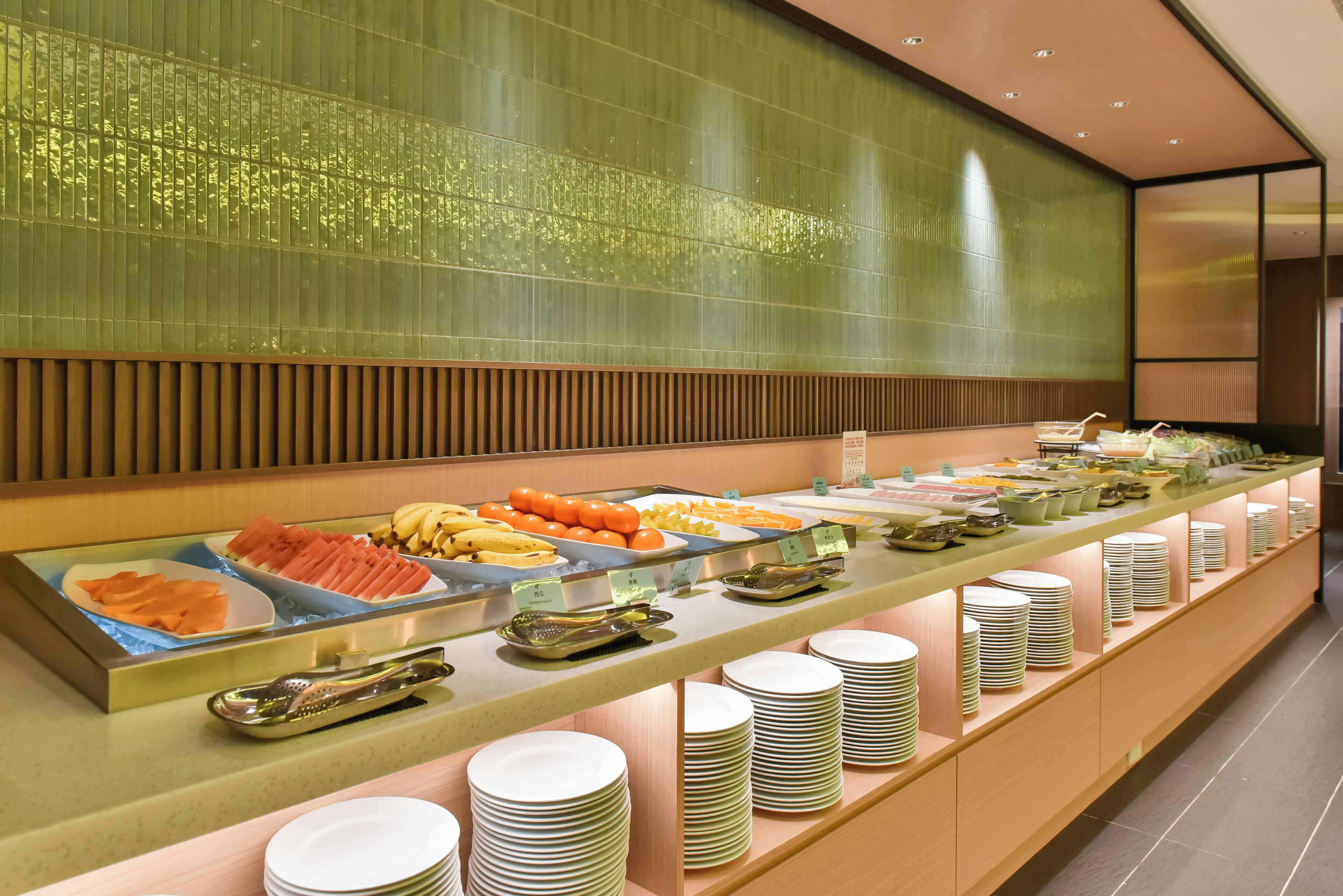 Buffet com diversos alimentos e pratos empilhados.