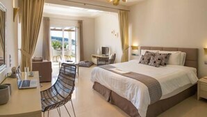 Quarto de hotel com uma cama grande, uma escrivaninha com um laptop, uma cadeira e uma televisão.