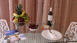 Uma mesa com uma fruteira, uma garrafa de vinho, uma taça de vinho, um prato com um guardanapo e um cardápio.
