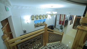 Uma escadaria com grades ornamentadas, um candelabro e uma parede com pratos decorativos e um quadro emoldurado.