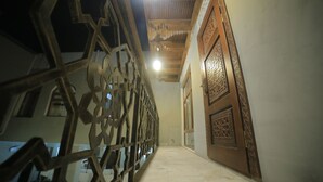 Um corredor com portas de madeira elaboradas e um portão de metal decorativo.