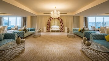 Uma sala de estar ampla com área de estar central, janelas grandes e um candelabro.