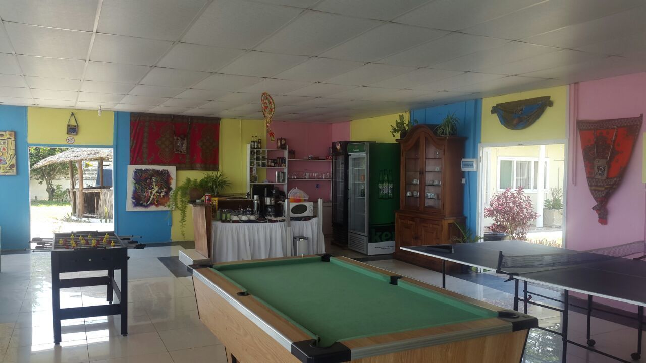 Quarto com mesa de bilhar, mesa de futebol e mesa de pingue-pongue. Paredes coloridas e janela com vista.
