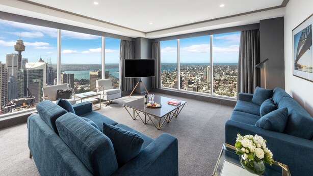 Uma sala de estar moderna com vista para a cidade, uma televisão de tela plana e uma mesa de centro.