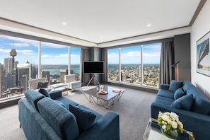 Uma sala de estar moderna com vista para a cidade, uma televisão de tela plana e uma mesa de centro.