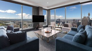 Uma sala de estar moderna com vista para a cidade, uma televisão de tela plana e uma área de jantar com mesa posta para dois.