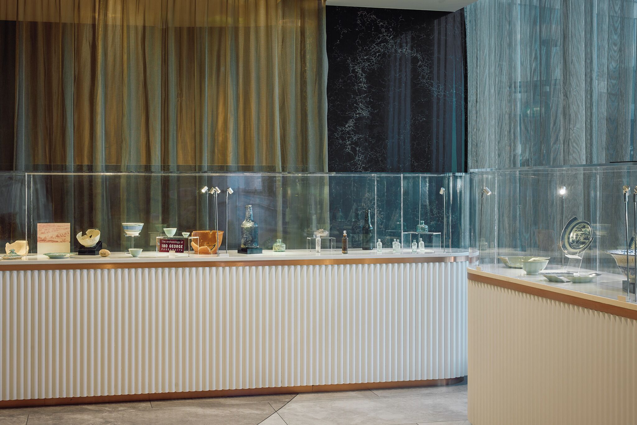 Uma área de recepção com uma vitrine de vidro contendo diversos artefatos.