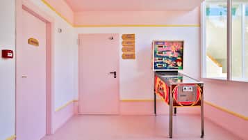 Um corredor com porta privativa, alarme de incêndio e uma mesa com pôster colorido.