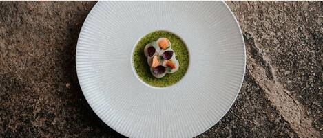 Um prato branco com molho verde e alimentos sobre uma superfície texturizada.