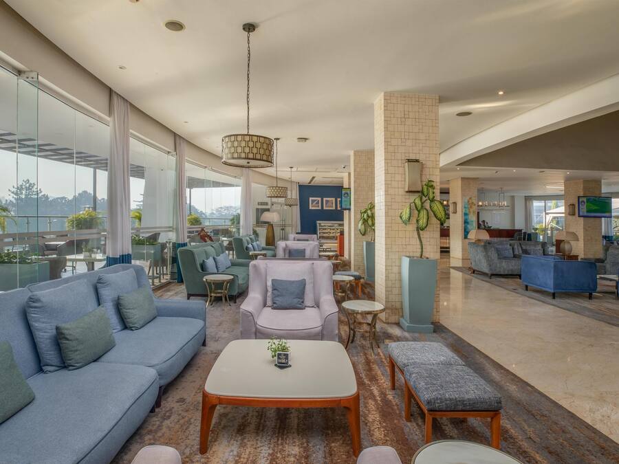 Um hall amplo com teto alto, mobiliário moderno e grandes janelas com vista para o exterior.