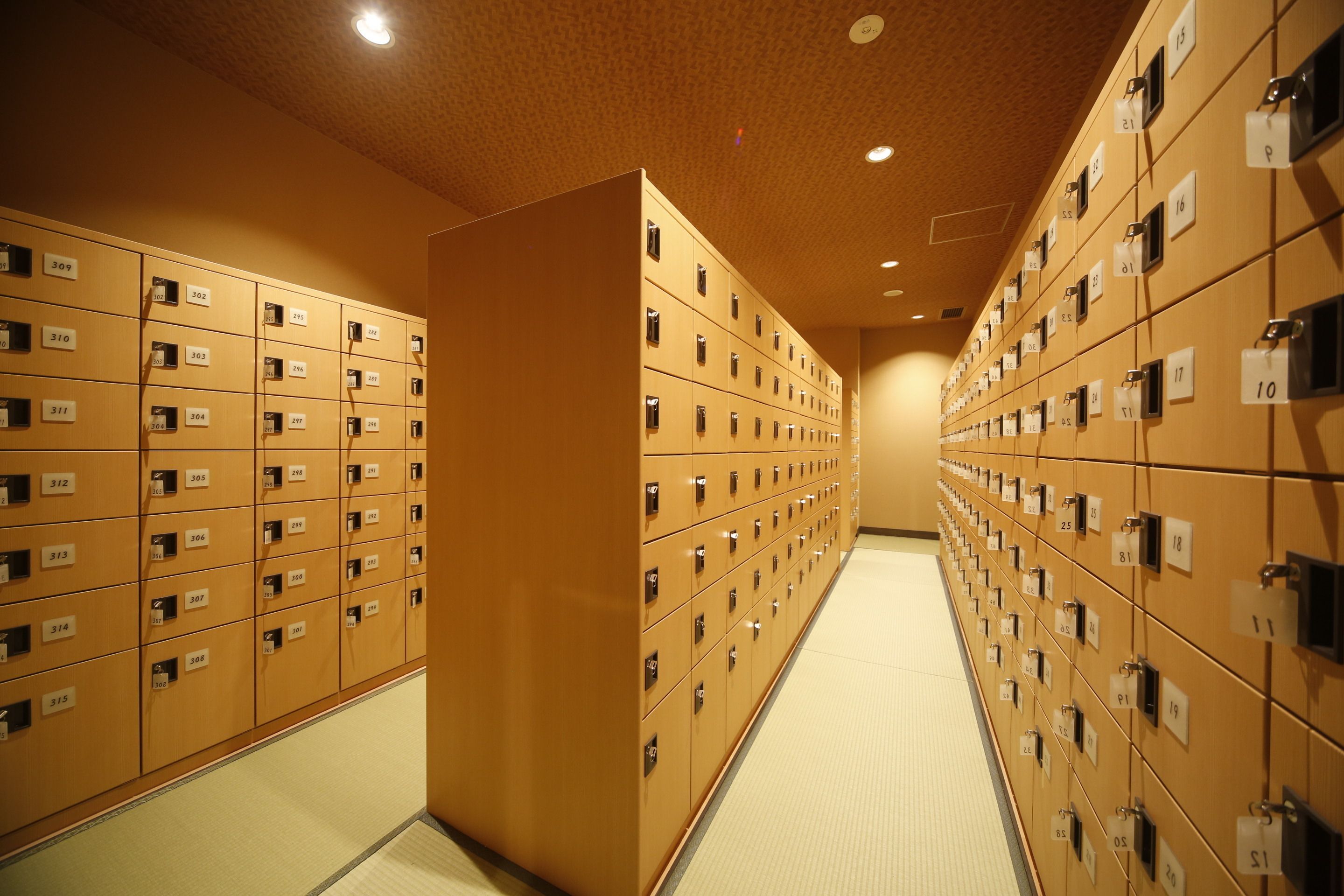 Corredor de hotel com fileiras de armários numerados.